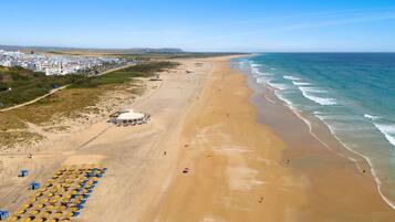 Na praia, praia de areia branca, espreguiçadeiras, guarda-sóis de praia