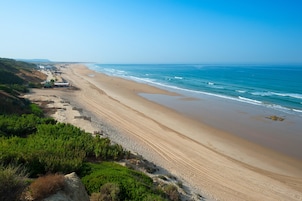 Na praia, areia branca, espreguiçadeiras, guarda-sóis 