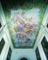 Um mural no teto com uma figura central e motivos florais.