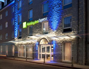 Edifício Holiday Inn Express com entrada de vidro e passarela coberta.
