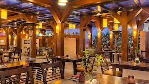 Restaurante com vigas de madeira, mesas e cadeiras.