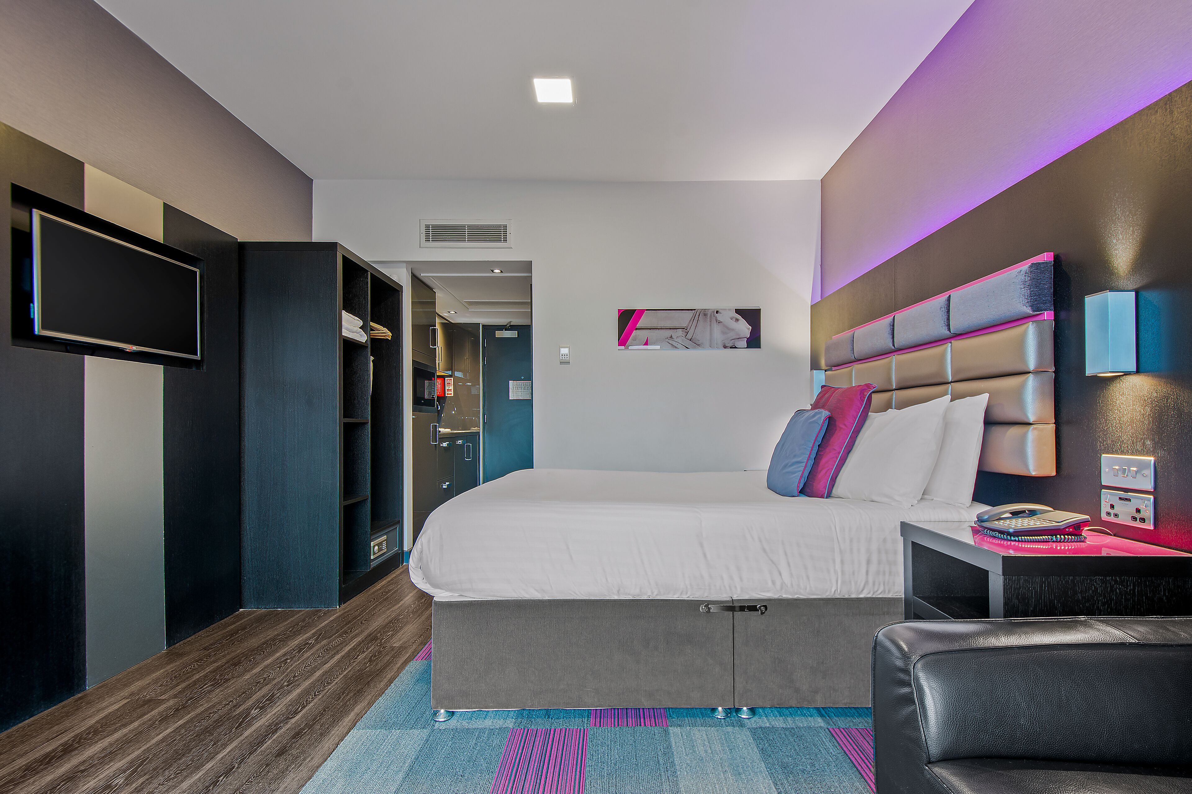 Quarto de hotel moderno com uma cama grande, uma escrivaninha e um guarda-roupa.