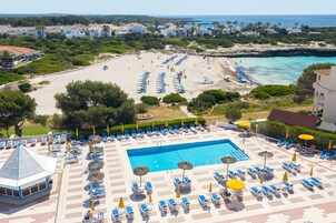Um resort com piscina, praia e área de estar.