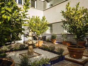Um pátio com uma fonte, plantas em vasos e uma parede de azulejos.