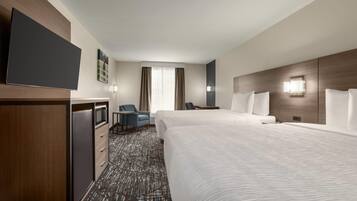 Quarto de hotel com duas camas, uma escrivaninha, uma cadeira, televisão e janela com cortinas.