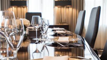 Uma mesa de jantar posta para uma refeição formal, com vários copos de vinho, pratos e talheres.