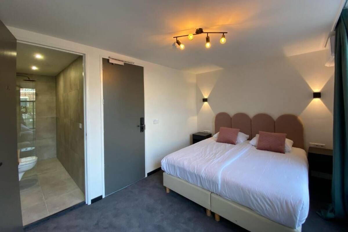 Quarto com cama, mesas de cabeceira e luminária no teto.