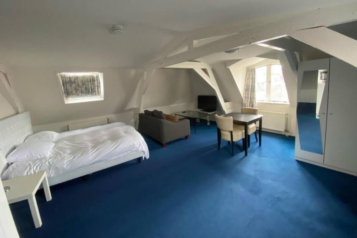 Quarto com cama, sofá, mesa de jantar e televisão.