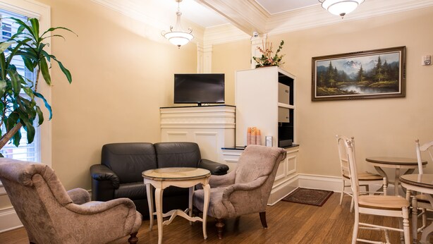 Uma sala de estar com lareira, televisão, pintura e um espaço de jantar com cadeiras e mesa.