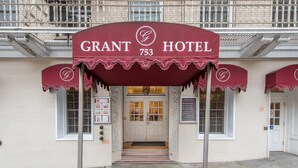 Exterior do Grant Hotel, com entrada destacada, varanda e vista clara das portas de entrada.