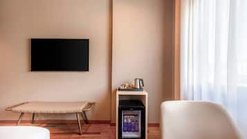 Quarto de hotel com televisão de tela plana, minibar, um banco e uma cadeira.