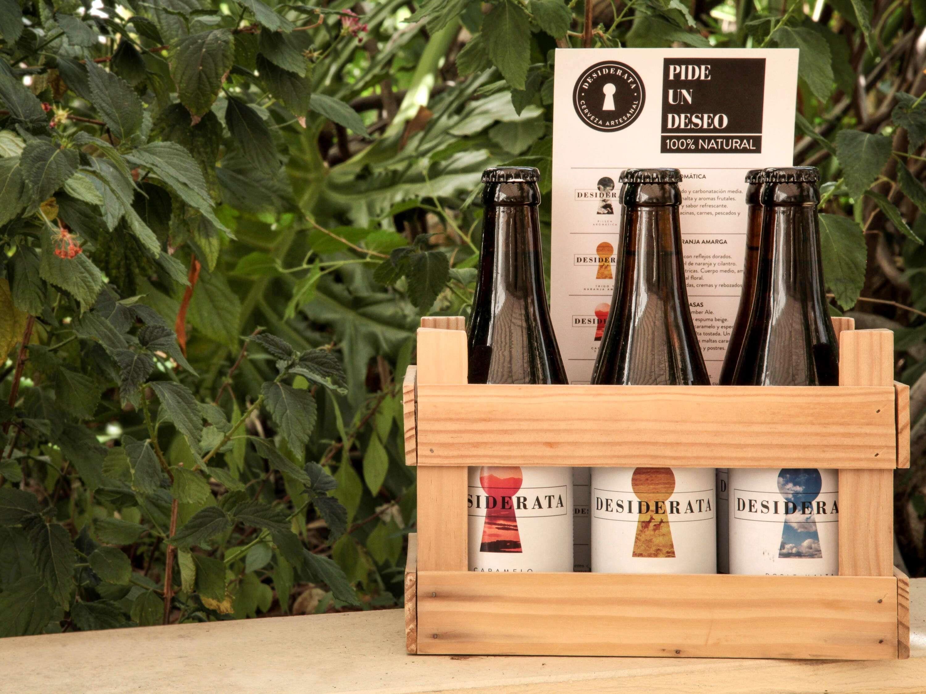Uma caixa de madeira com quatro garrafas de vinho Desiderata, com etiqueta indicando que é 100% natural.