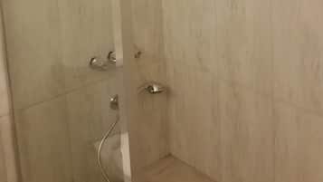 Chuveiro com porta de vidro, porta-toalhas e chuveiro.