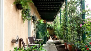 Uma área de estar coberta ao ar livre, com cadeiras e plantas em vasos.