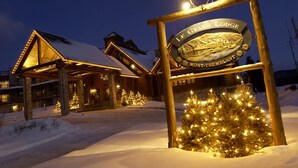 Uma cabana com telhado coberto de neve e árvores de Natal iluminadas.