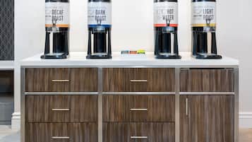 Uma estação de café com quatro dispensadores identificados como Café Descafeinado, Café Torra Escura, Água Quente e Café Torra Clara.
