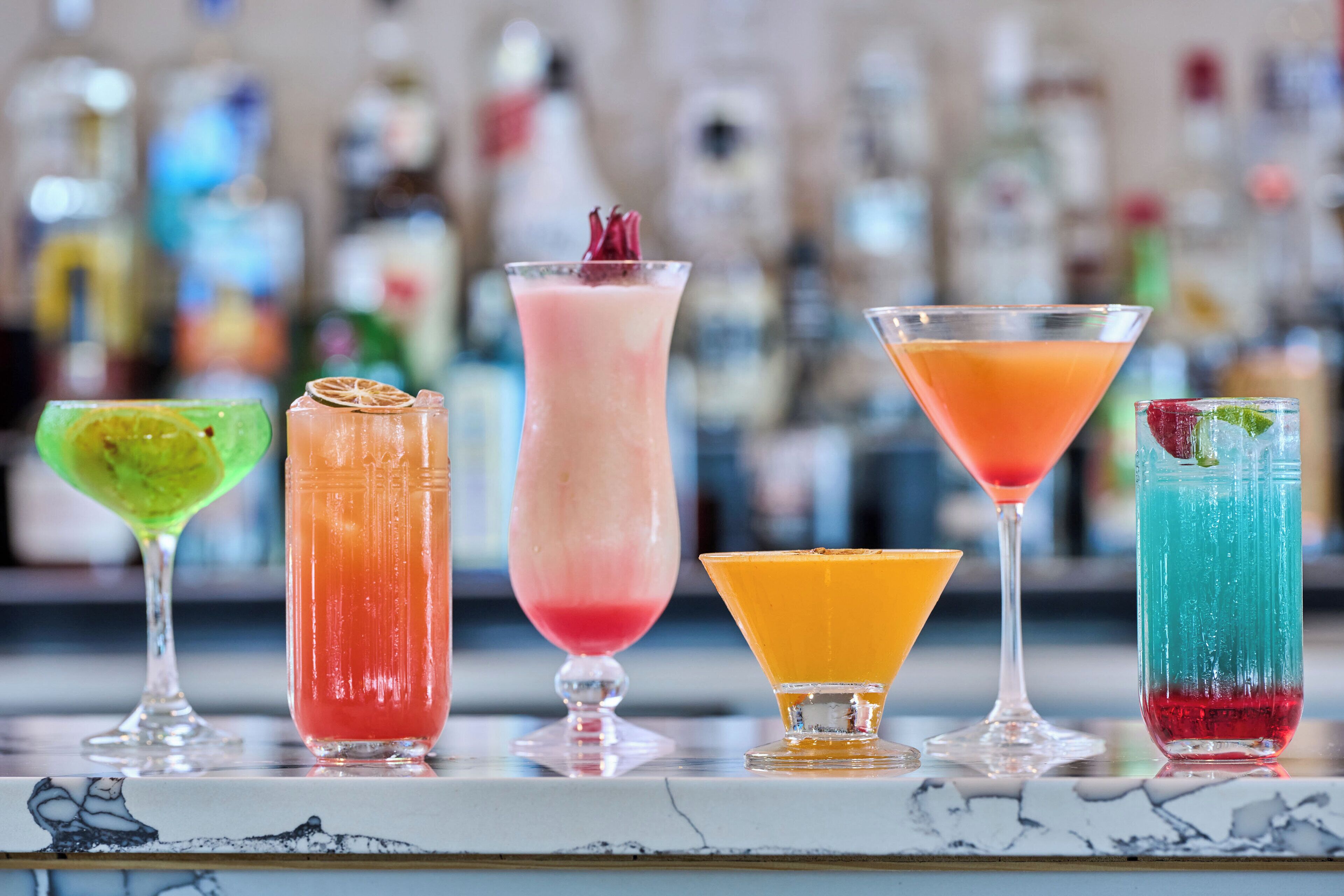 Um bar com vários cocktails coloridos em diversos copos.