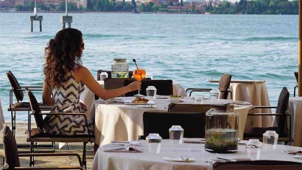 Uma mesa de jantar com vista para a água e um edifício ao longe.