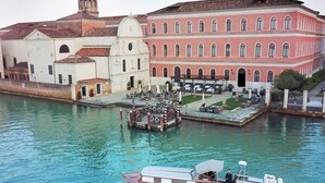 Um barco chamado 'San Clemente Palace' atracado em uma orla com um edifício histórico ao fundo.