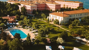 Um hotel espaçoso com piscina, rodeado por vegetação exuberante e vista para o mar.