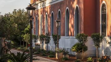 Um edifício de tijolos vermelhos com janelas em arco e um jardim frontal.