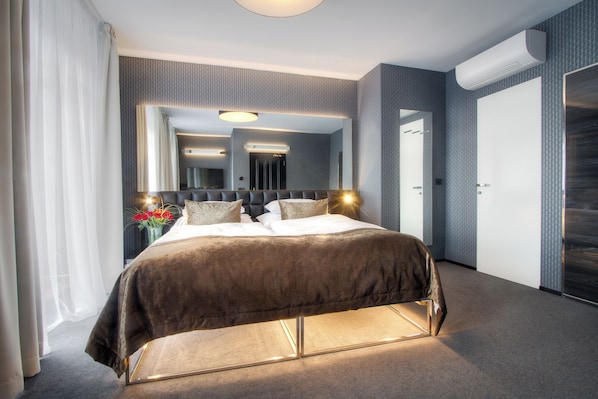 Quarto de hotel moderno com uma cama grande, um espelho e unidade de ar condicionado integrada.