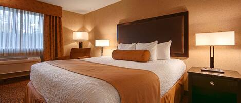 Quarto de hotel com uma cama grande, duas luminárias de cabeceira, uma cabeceira, um criado-mudo e um armário verde.
