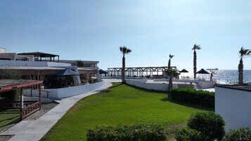 Um resort com piscina, palmeiras e vista para o mar.