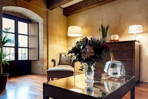 Um quarto acolhedor com piso de madeira, uma mesa de vidro com um vaso de flores, um sofá e um armário com uma luminária.