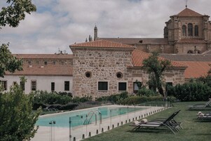 Um edifício de pedra com piscina e espreguiçadeiras.