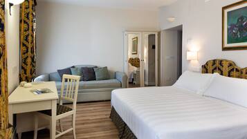Quarto de hotel com cama, escrivaninha, cadeira, sofá e guarda-roupa.