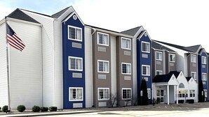 Um edifício residencial de vários andares com entrada central, janelas e uma bandeira americana.