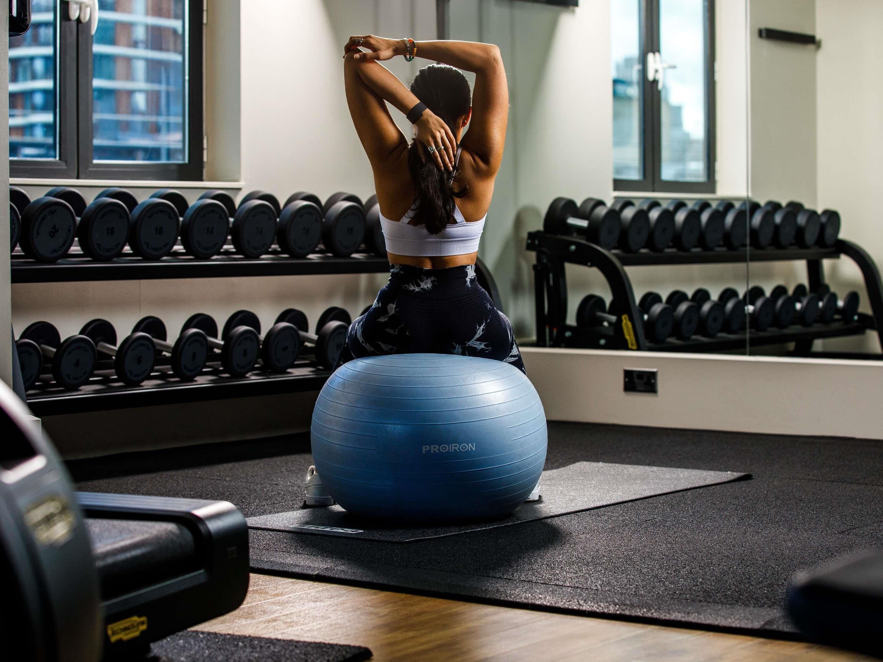 Uma academia com equipamentos de ginástica, incluindo uma bola de exercícios azul e halteres.