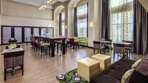 Um amplo saguão de hotel com área de refeições, assentos e grandes janelas.