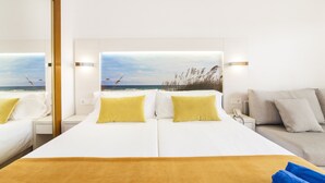 Quarto de hotel com cama, sofá e vista para o mar.