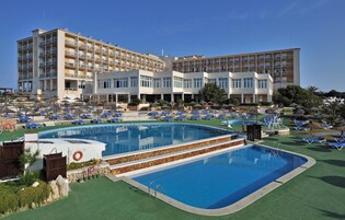 Hotel com uma piscina grande, várias varandas e uma área de gramado bem cuidada.