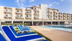Um hotel com várias varandas, piscina e espreguiçadeiras.