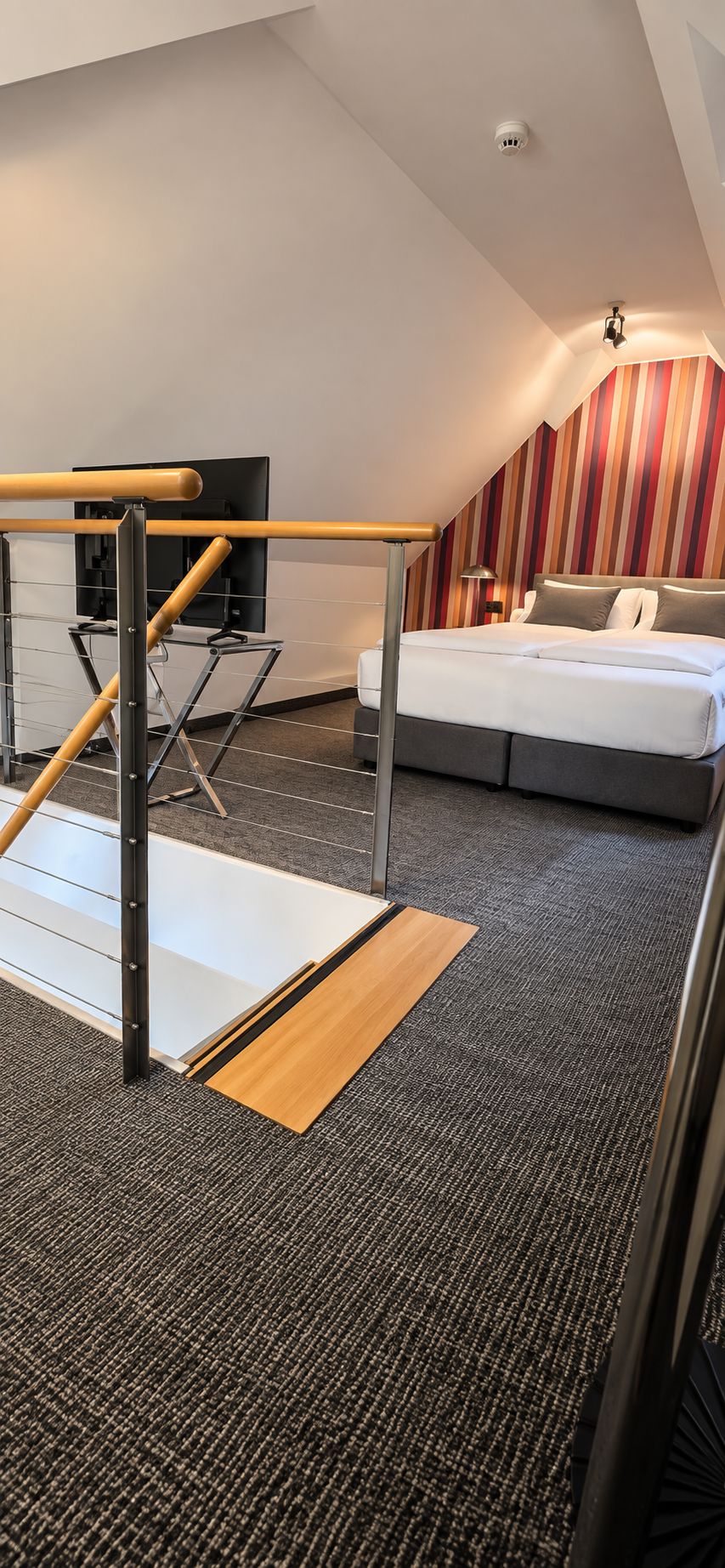 Quarto de hotel com cama, escrivaninha, cadeira, televisão e câmera de segurança instalada no teto.