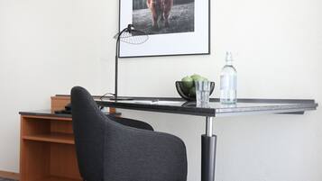 Uma mesa de escritório moderna com um quadro de uma vaca das Terras Altas, um copo de água e uma maçã verde sobre a mesa.