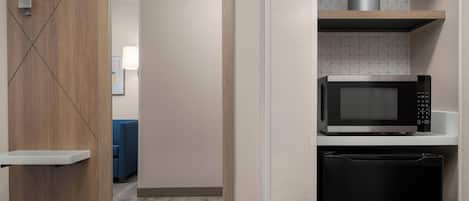 Cozinha moderna com micro-ondas, lava-louças e armário de madeira com porta deslizante.