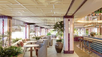 Um interior moderno com área de bar, assentos e plantas em vasos.