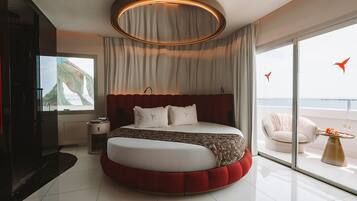 Um quarto moderno com cama circular, TV, varanda com vista e luminária de teto redonda.