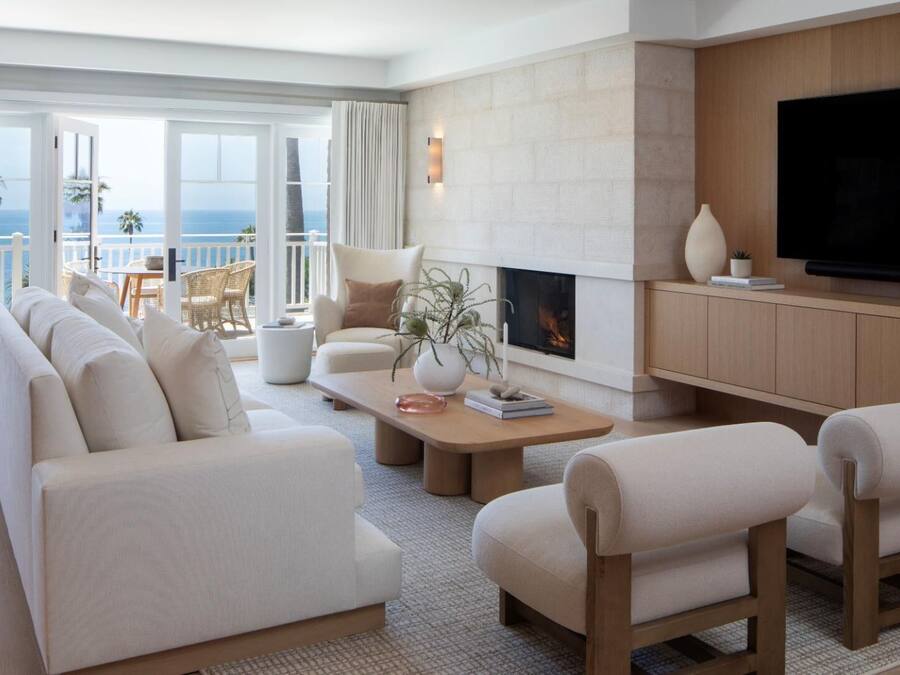 Sala de estar moderna com lareira, televisão de tela plana e varanda com vista para o oceano.