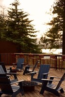 Um deck externo com cadeiras Adirondack e uma lareira.