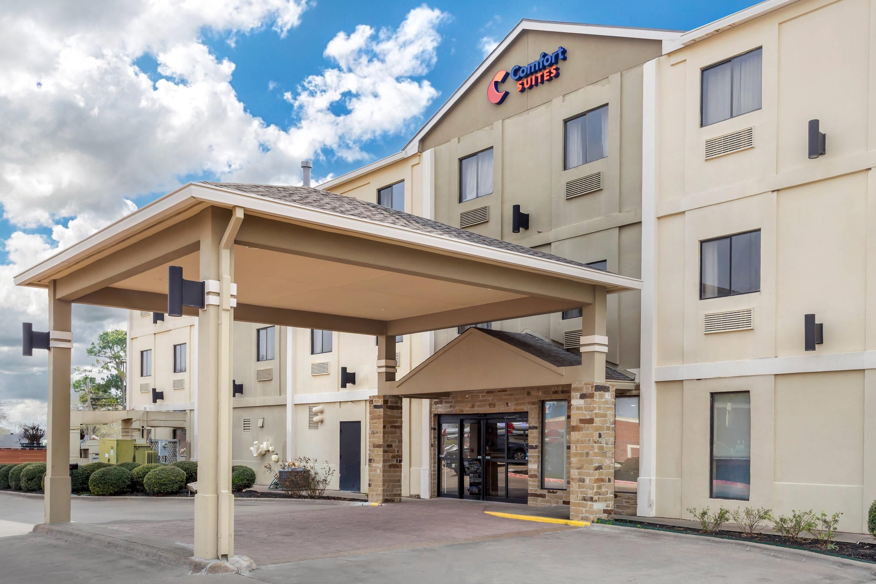 Um hotel com entrada coberta, diversas janelas e a placa Comfort Suites.