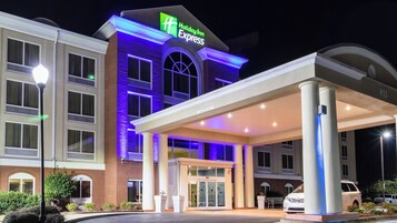 Um hotel Holiday Inn Express com entrada coberta, sinalização clara e área de estacionamento.