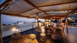 Terraço no telhado com assentos de fibra natural, vista da cidade e um edifício moderno ao fundo.