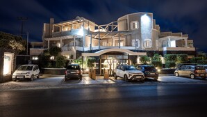 Hotel moderno com ampla área de estacionamento e vários carros estacionados.