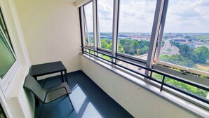 Uma varanda com vista para a cidade, uma mesa pequena e uma cadeira.