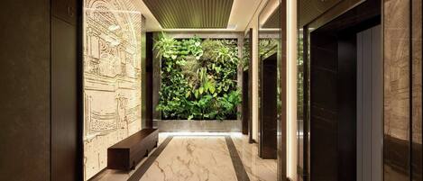 Um corredor moderno com piso de mármore, parede verde com plantas e teto de madeira.